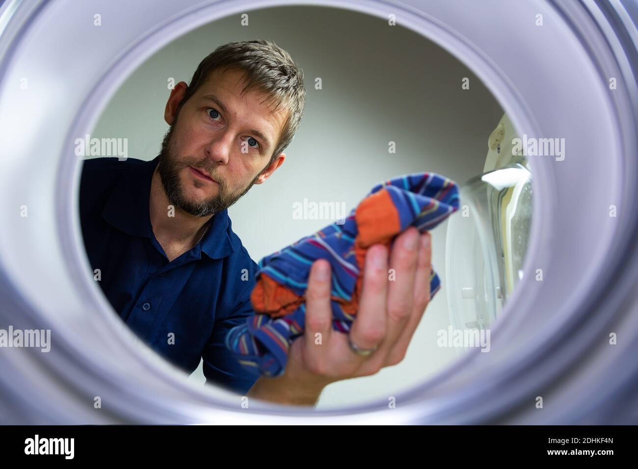 Young caucasian man loading washing machine. Man making houseworks ...