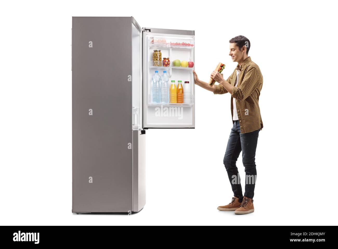 Happy man with a sandwich standing in front of a fridge isolated on ...