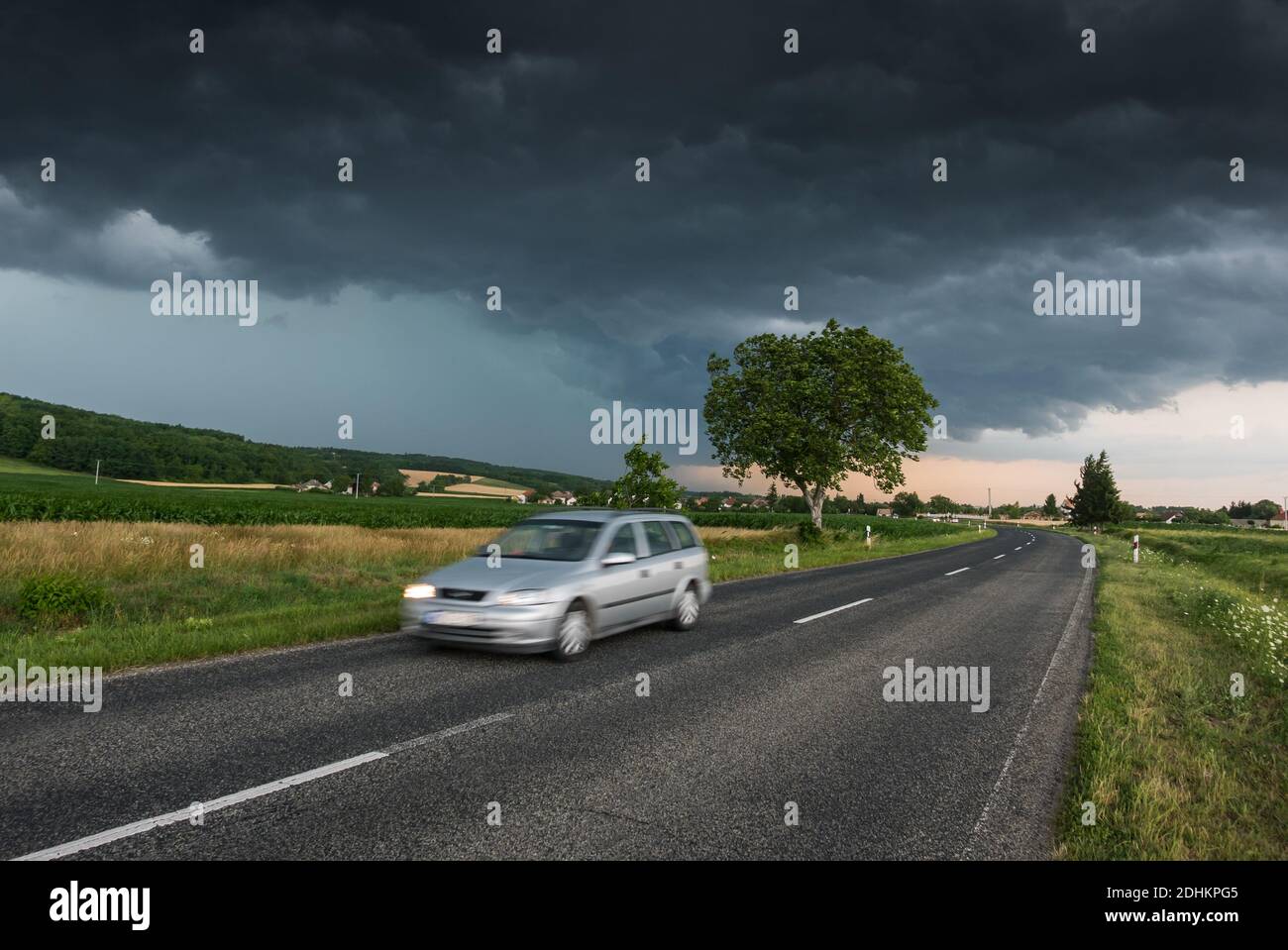 car on asphalt road under stormy sky with clouds Stock Photo - Alamy
