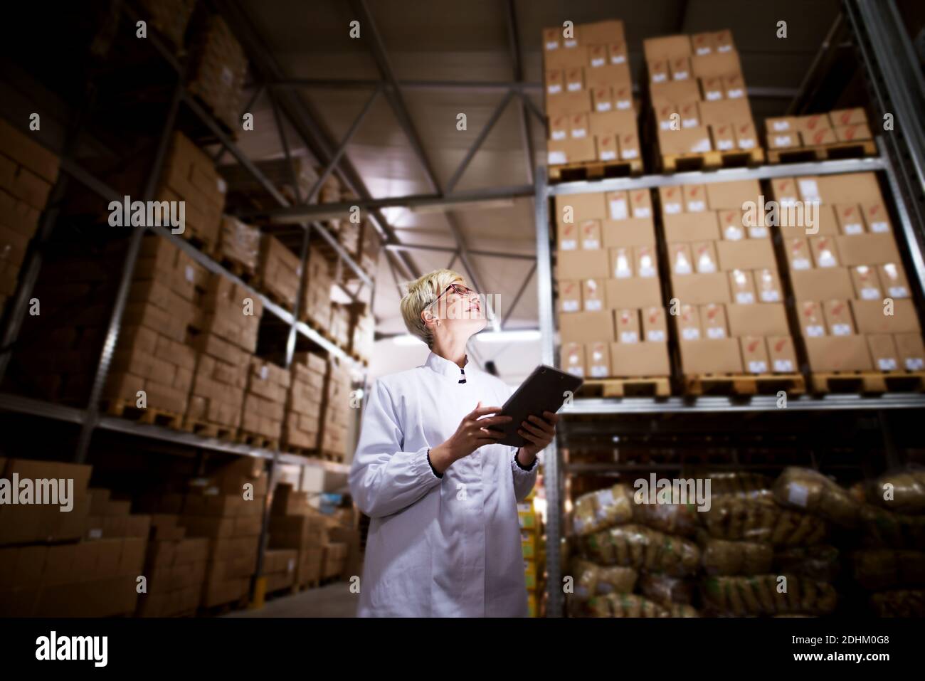 Young cheerful gorgeous worker is using a tablet to check if production ...