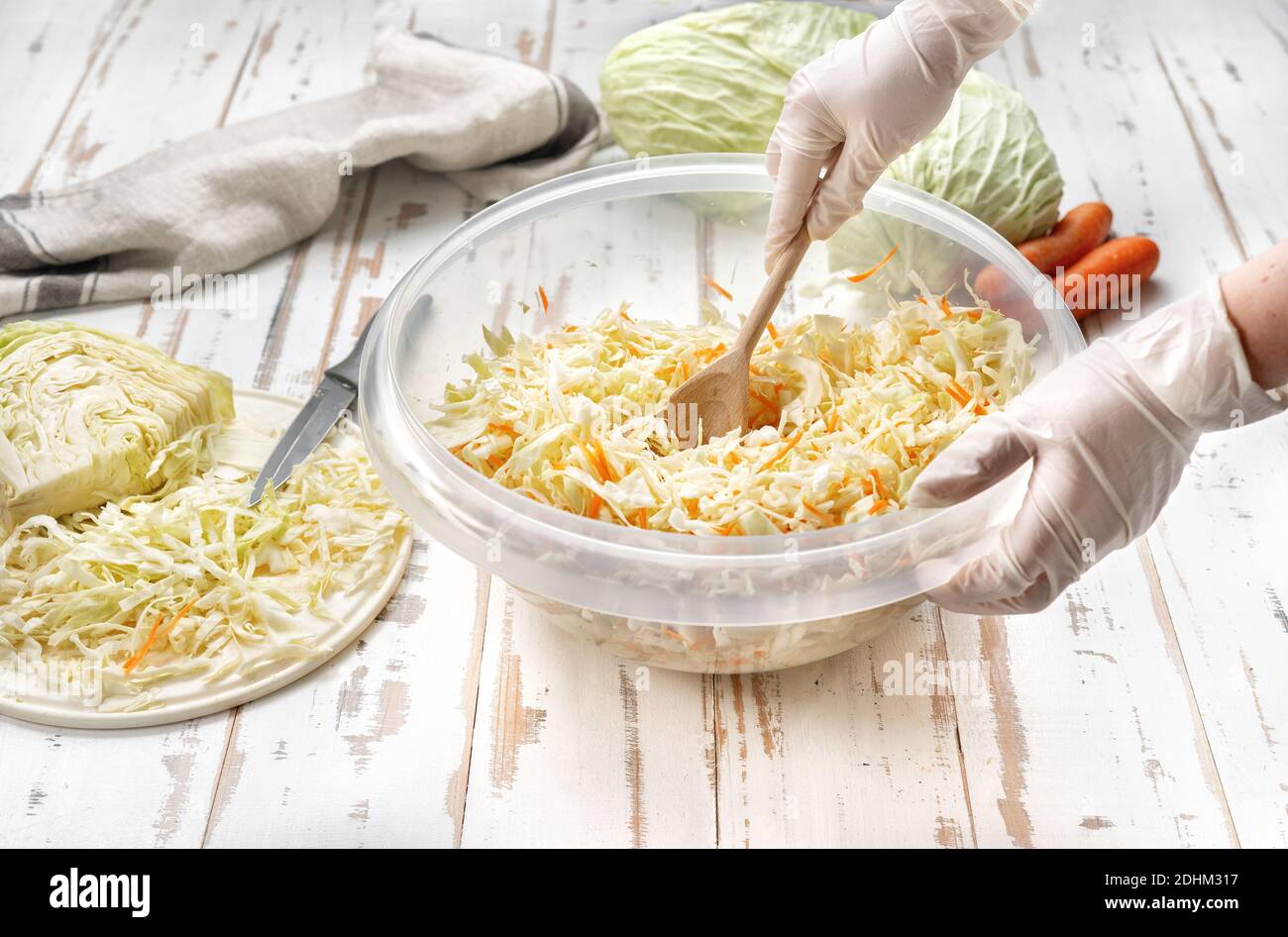 Female hands in gloves mixing chopped cabbage in a big bowl. Sauerkraut ...