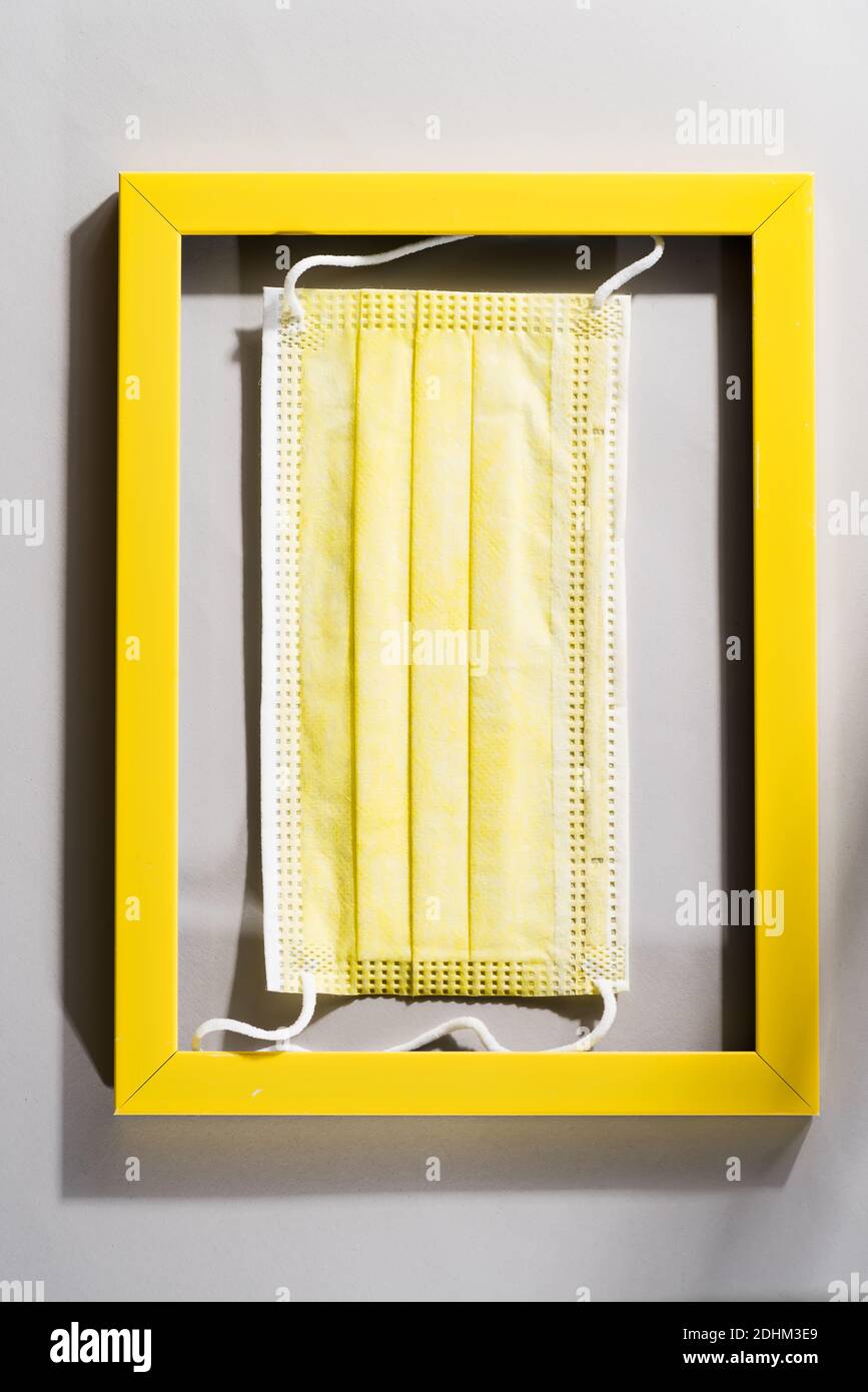 Yellow surgical face protection mask in the yellow frame on gray ...