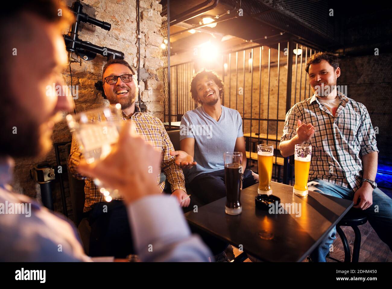 Four happy casual multicultural friends having fun and drinking beer ...