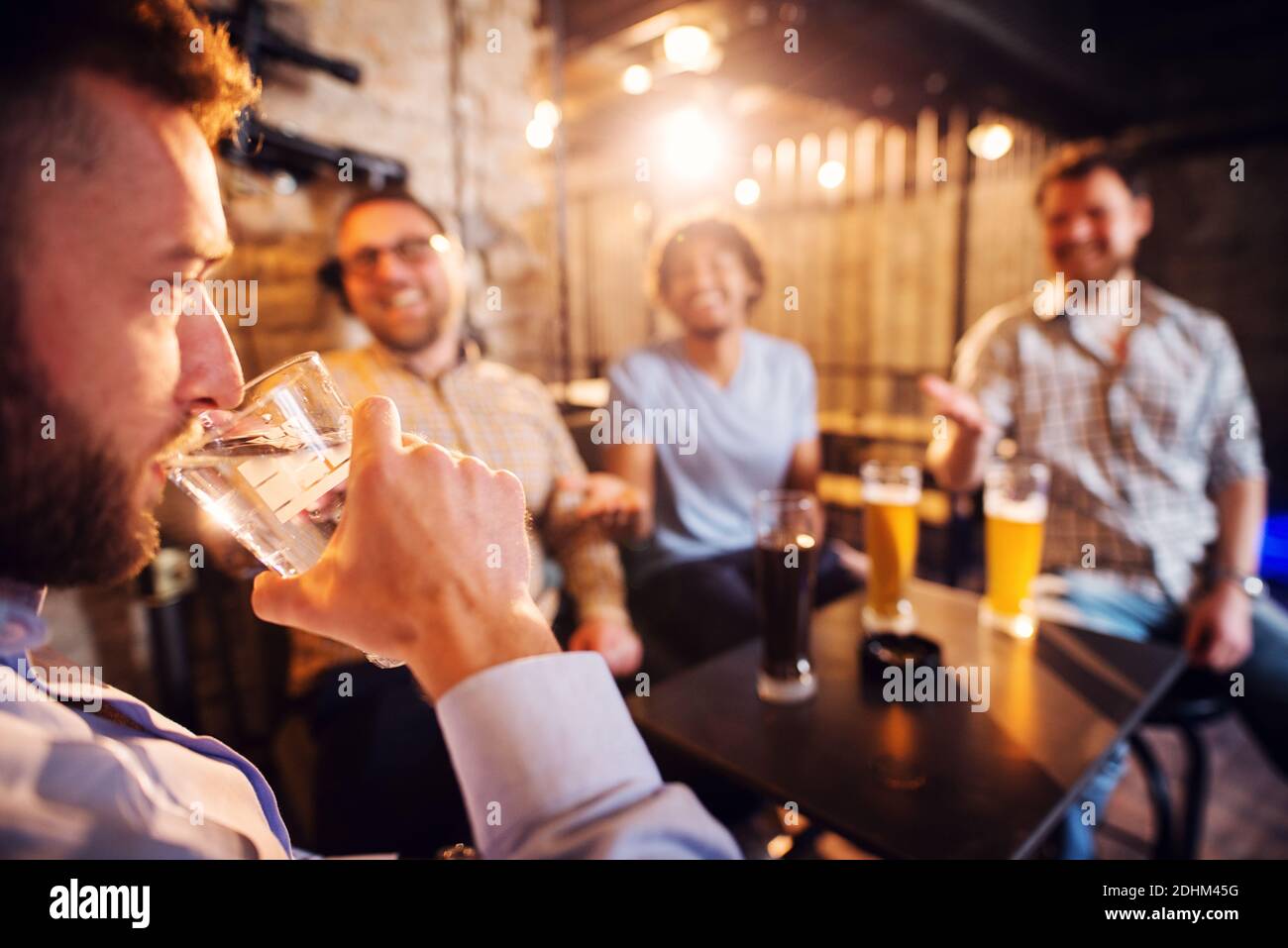 Handsome man drinking a glass of water in the local pub while his ...