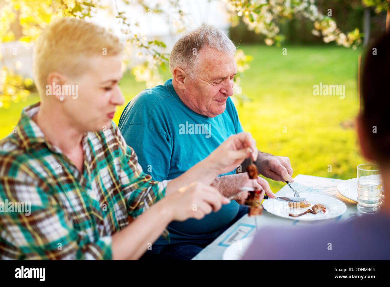 Elderly man and mature woman are sitting at the table outside under the ...