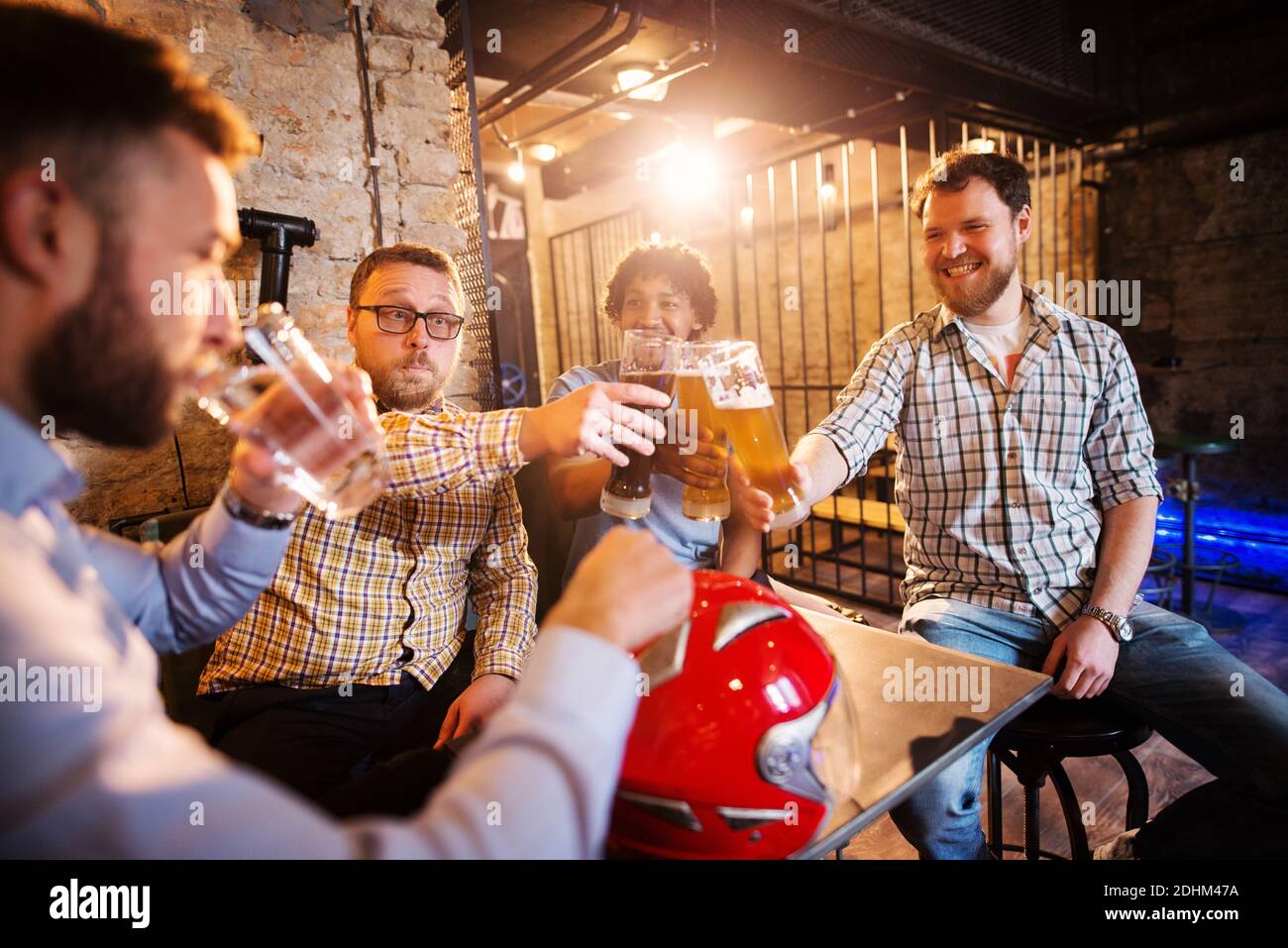 Joyful male friends clinking with draft beer in front of their friend ...