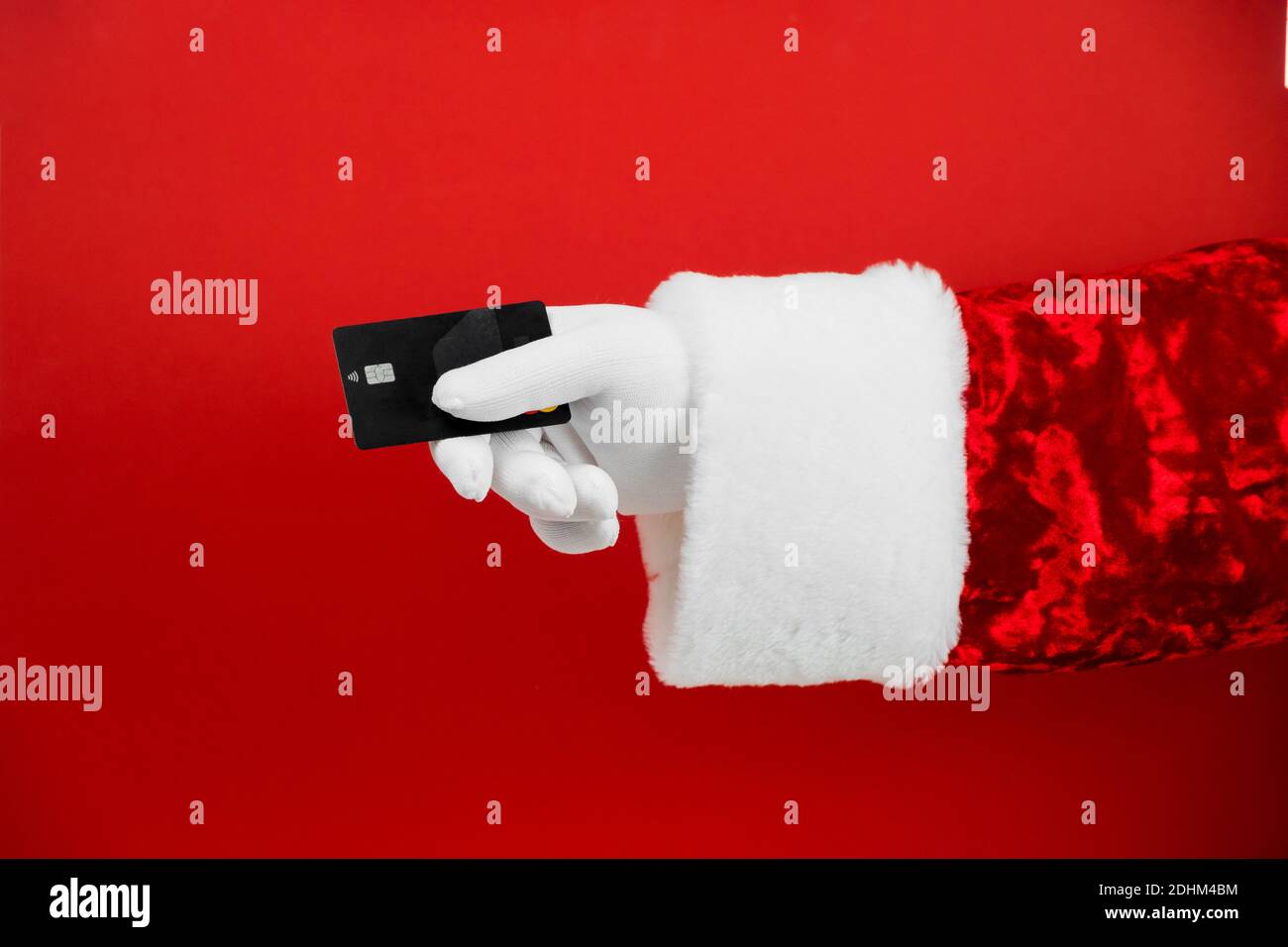 Santa Claus hand holding blank black plastic credit card on red ...