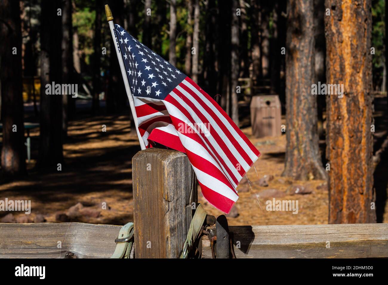 A tattered American flag on a fence post in sunlight Stock Photo - Alamy