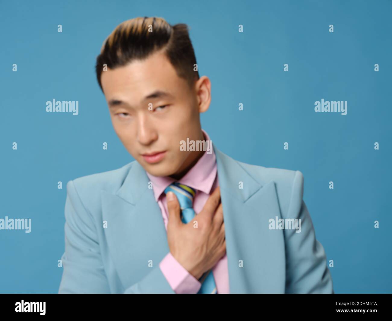 A man in a jacket and shirt straightens his tie around his neck Asian ...