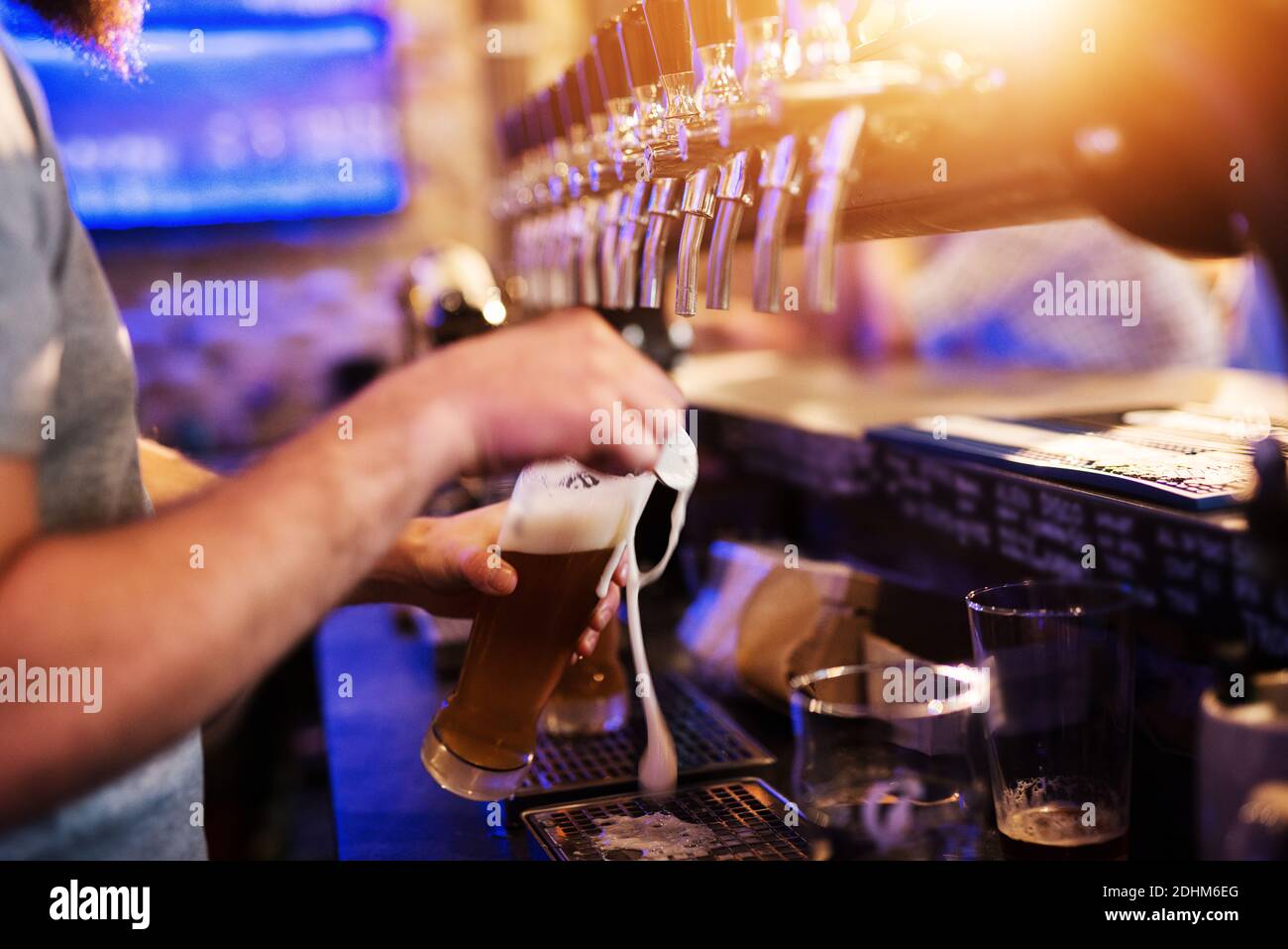 Close up focus view of bartender hand pouring draft beer and taking off foam Stock Photo - Alamy
