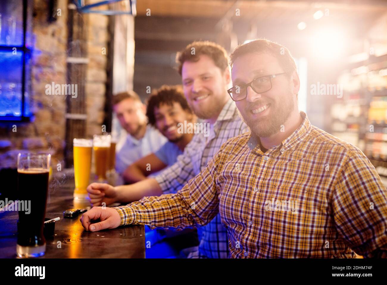 Row of men sitting in the bar with light and dark draft beer and ...