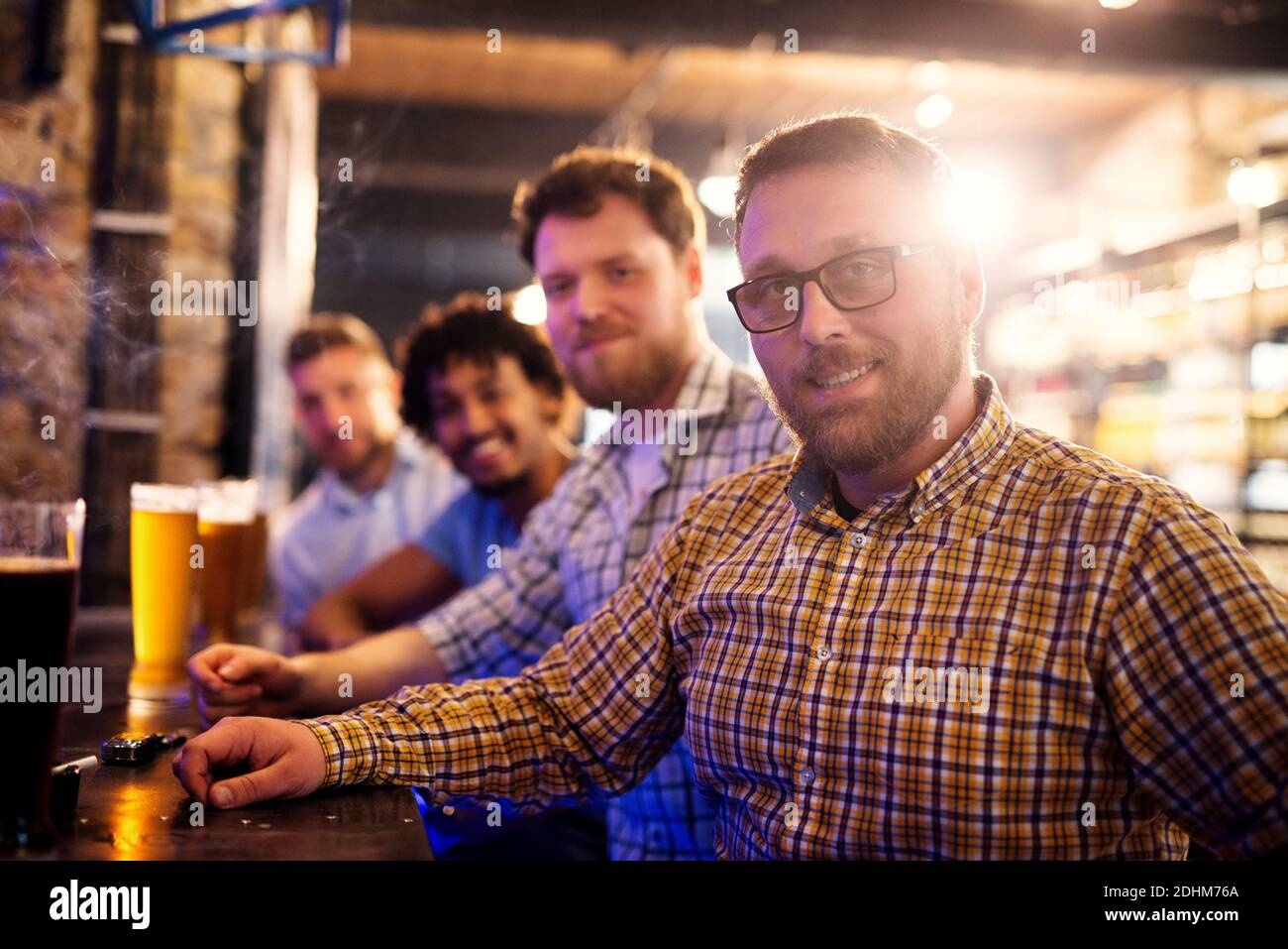 Portrait of handsome smiling man sitting in the bar with friends and ...