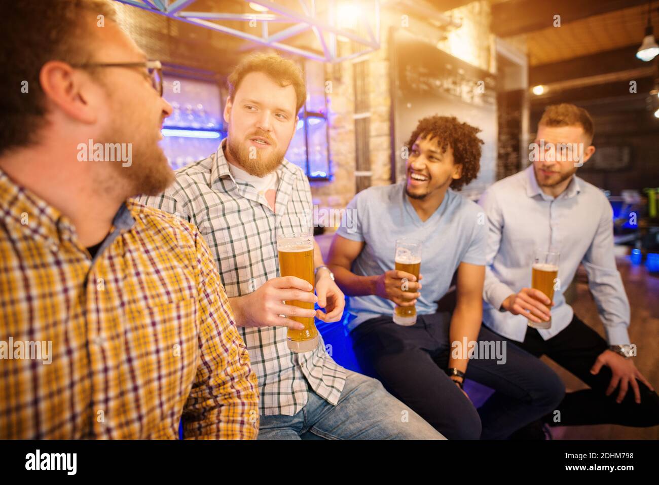 Four curious multicultural friends sitting on the bar chair and ...