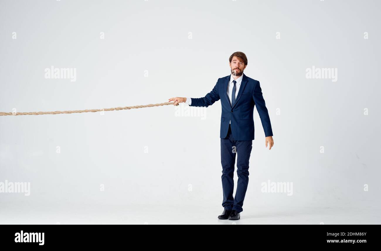 business man in a suit pulls a rope on a light background Stock Photo ...