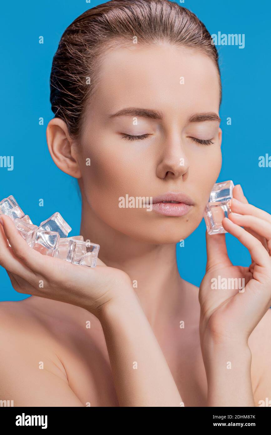 Beautiful woman applying ice cube treatment on blue background Stock ...