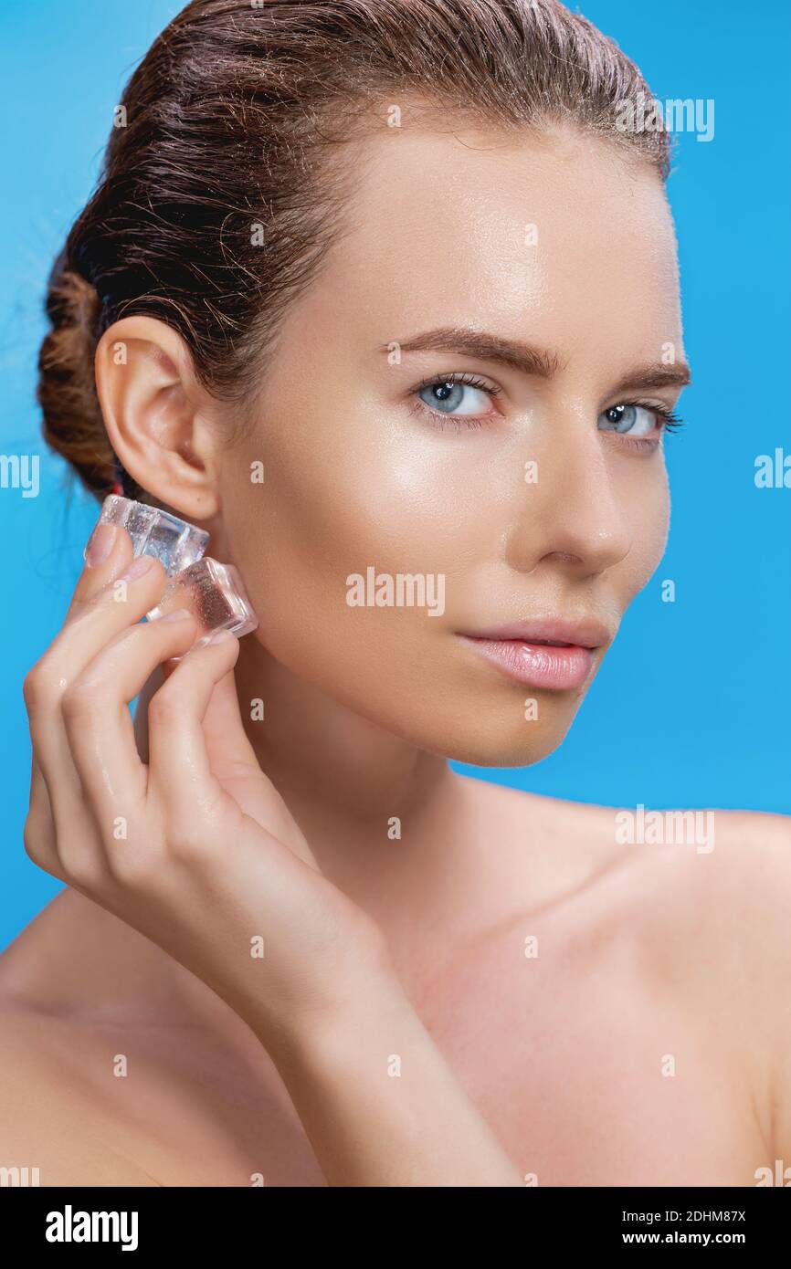 Beautiful woman applying ice cube treatment on blue background Stock ...