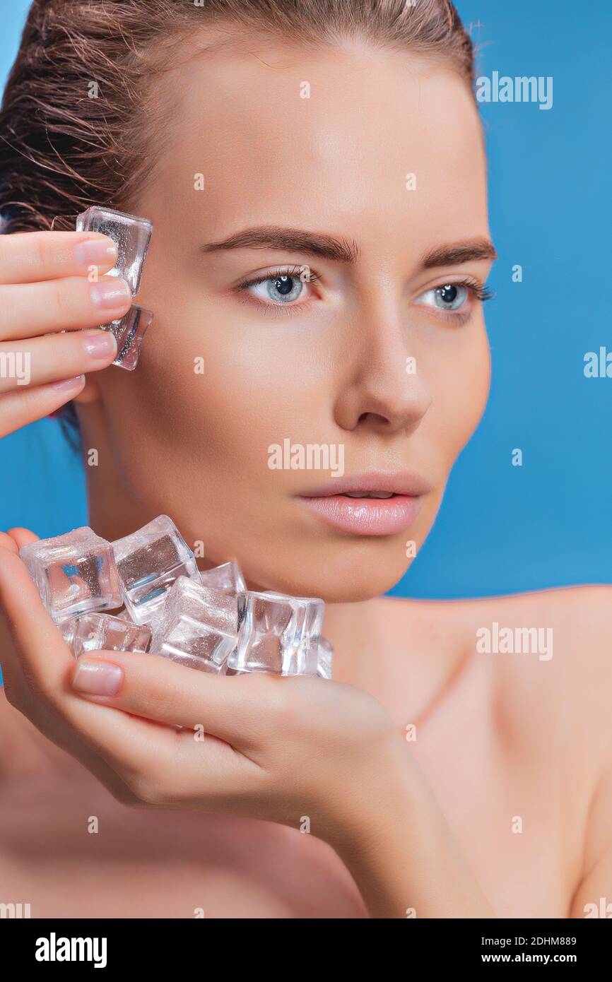 Beautiful woman applying ice cube treatment on blue background Stock ...