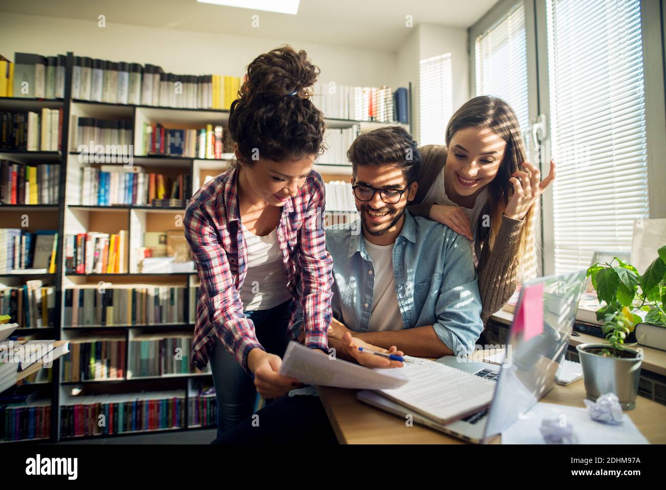 Group of young friendly cheerful students is studying from scripts and ...