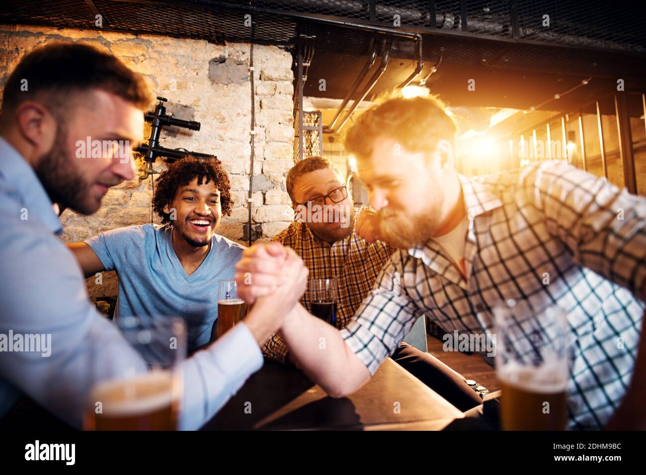 Group of joyful happy men having fun in the pub. Two friends arm ...
