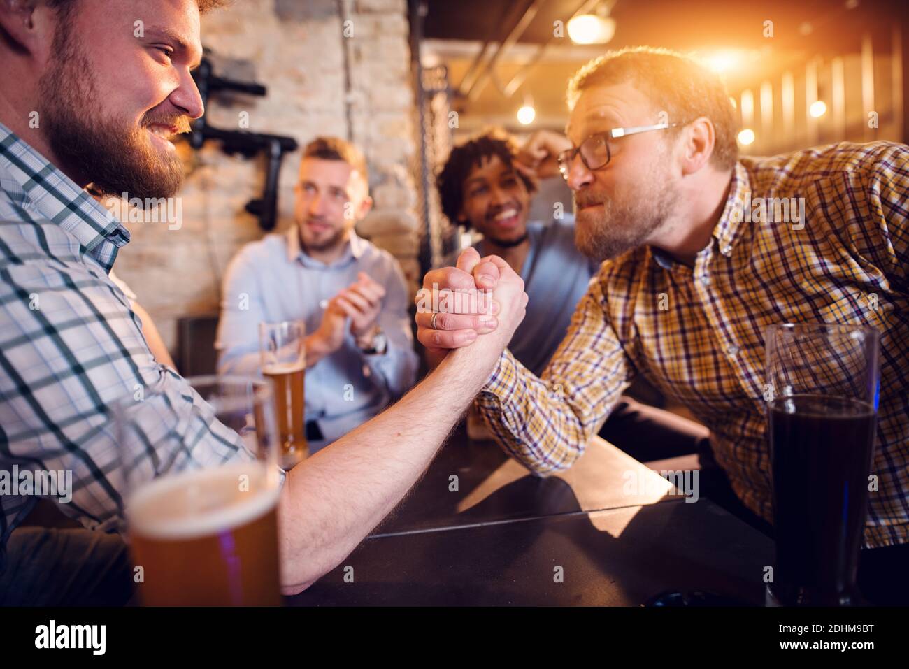 Prepared and focused male friends looking each other while having arm ...
