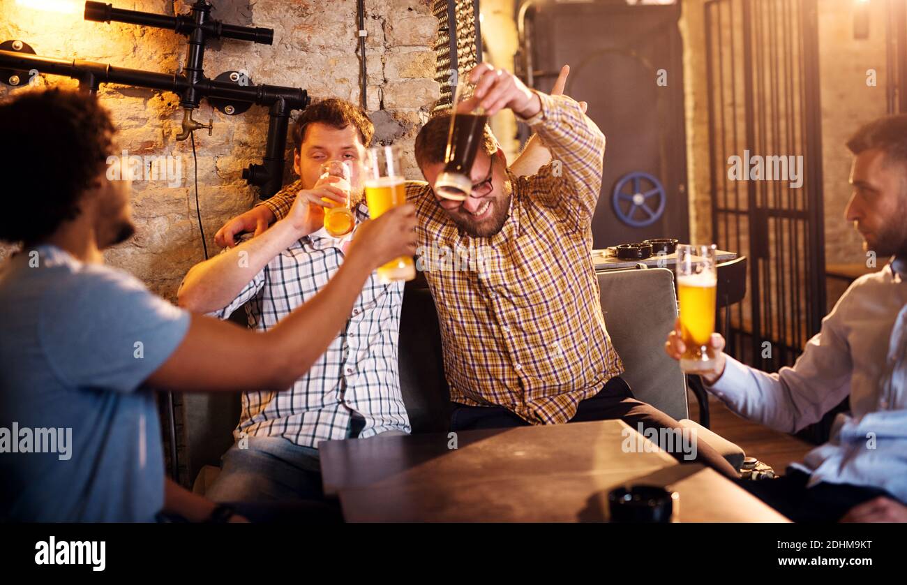 Four multicultural satisfied drunk friends sitting in the bar and ...