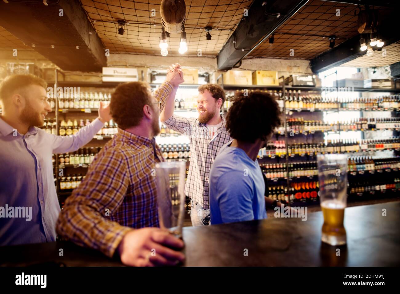 Happy cheerful man coming to the pub and shaking hands with friends ...