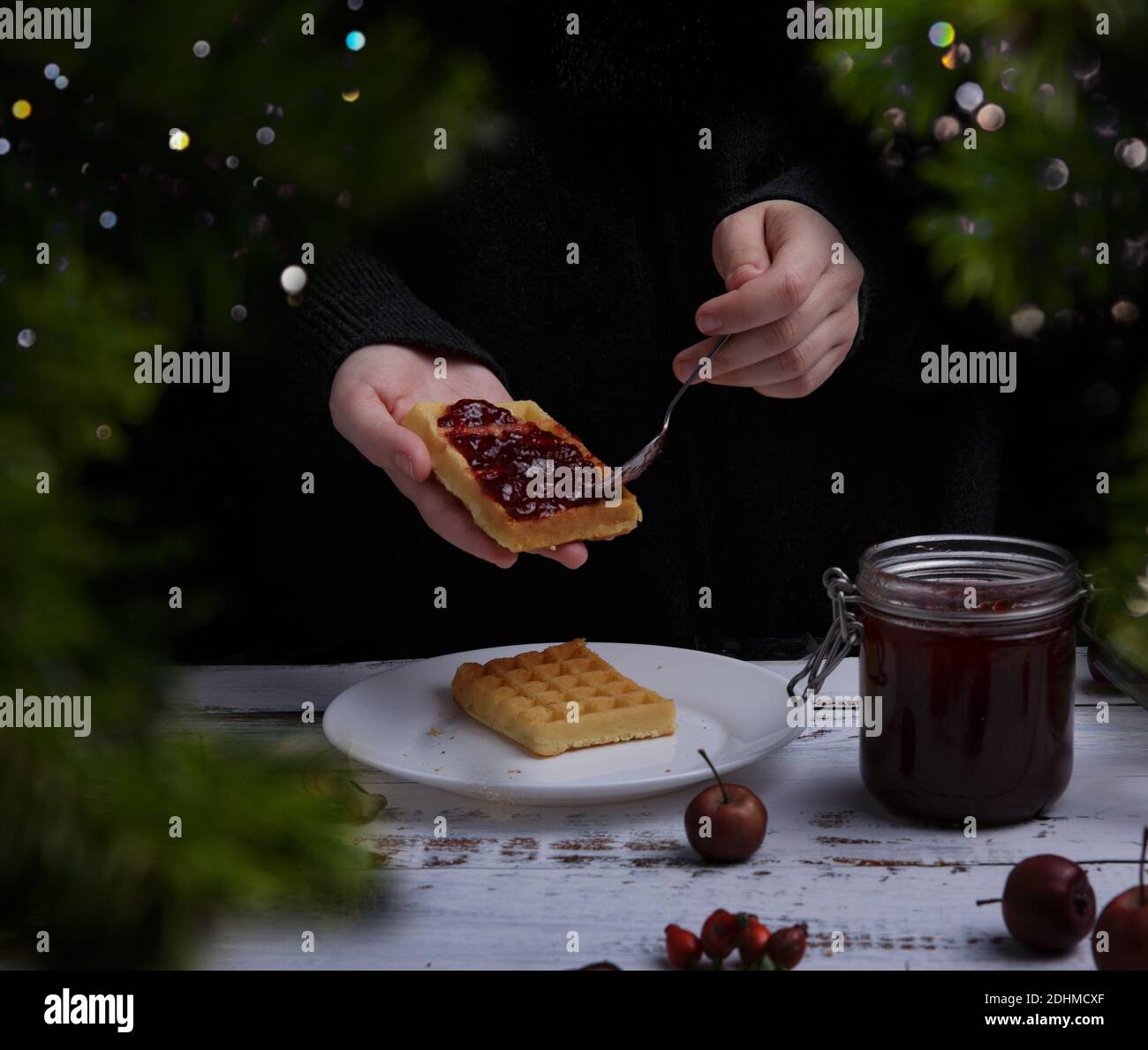 hand smear jam on waffles . Nearby Christmas tree . concept of ...