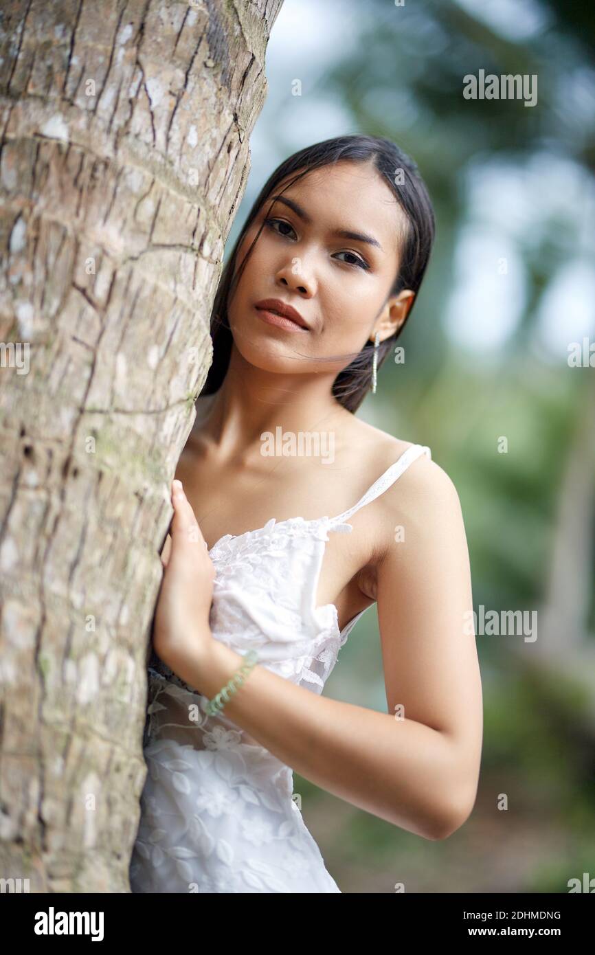 Close-up portrait young beautiful Asian girl crazy face with palm tree. Smiling to the camera ...