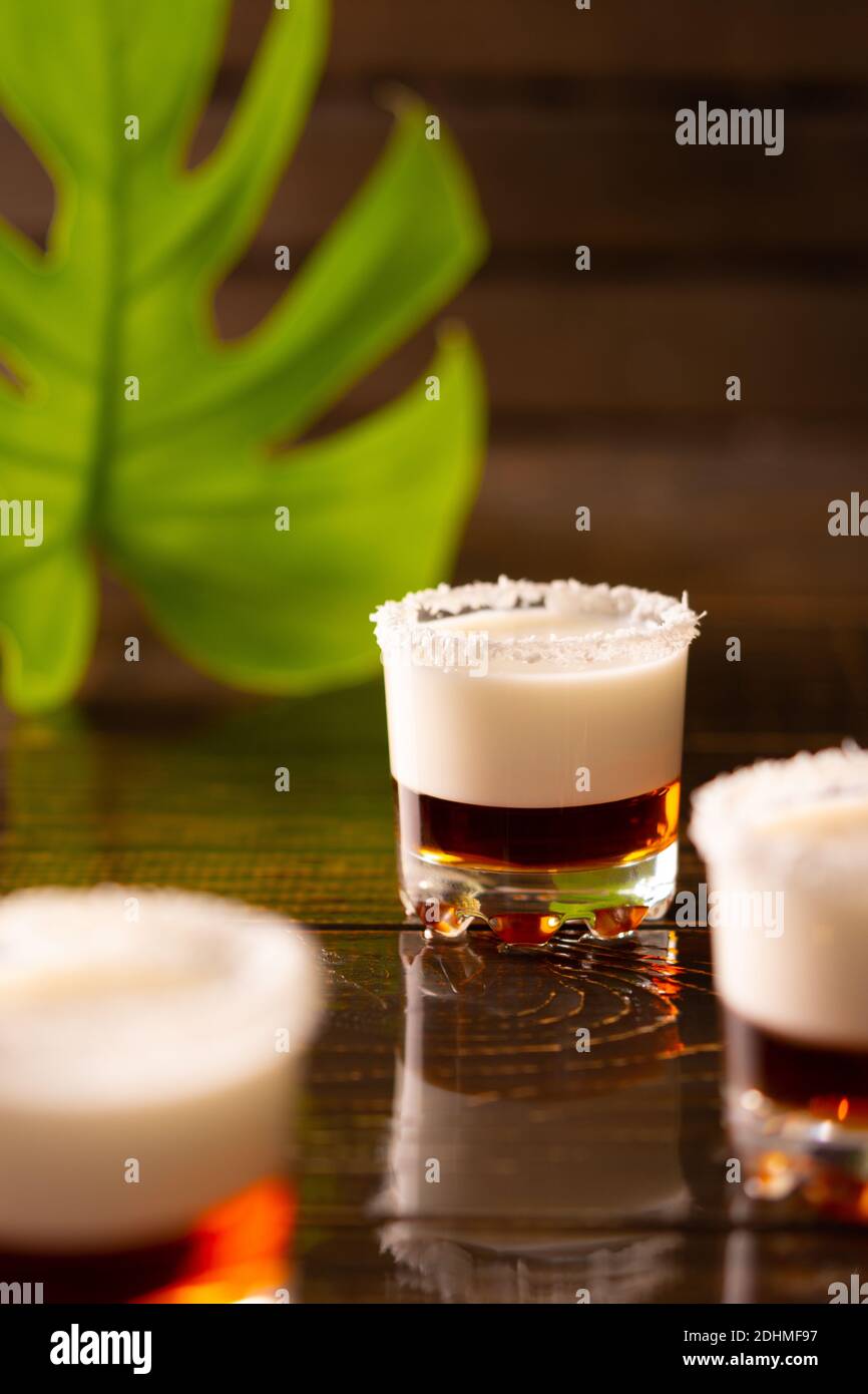 Tropical alcoholic shots decorated with coconut flakes, monstera flower ...