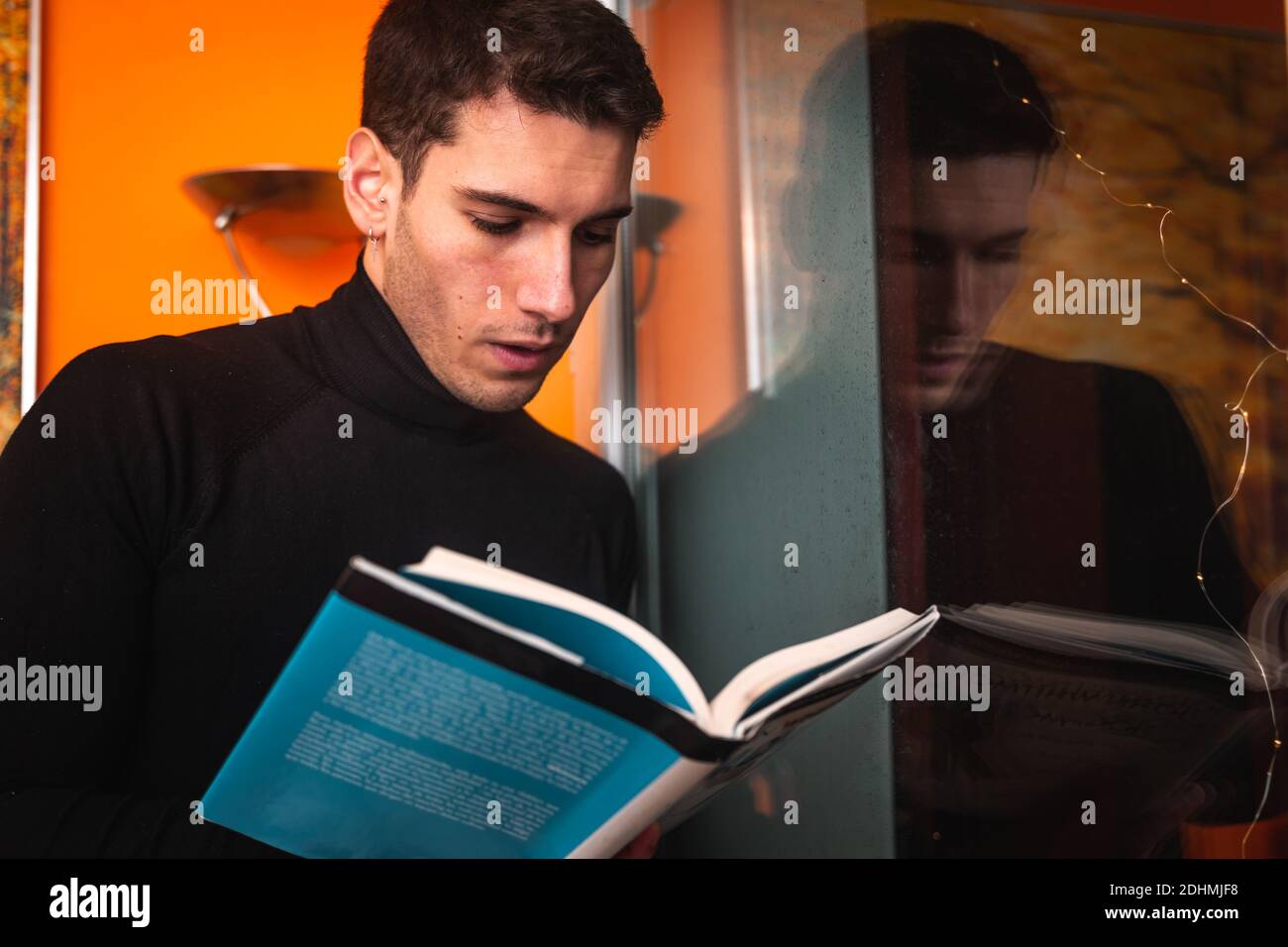 Young man reading a book next to the window Stock Photo - Alamy