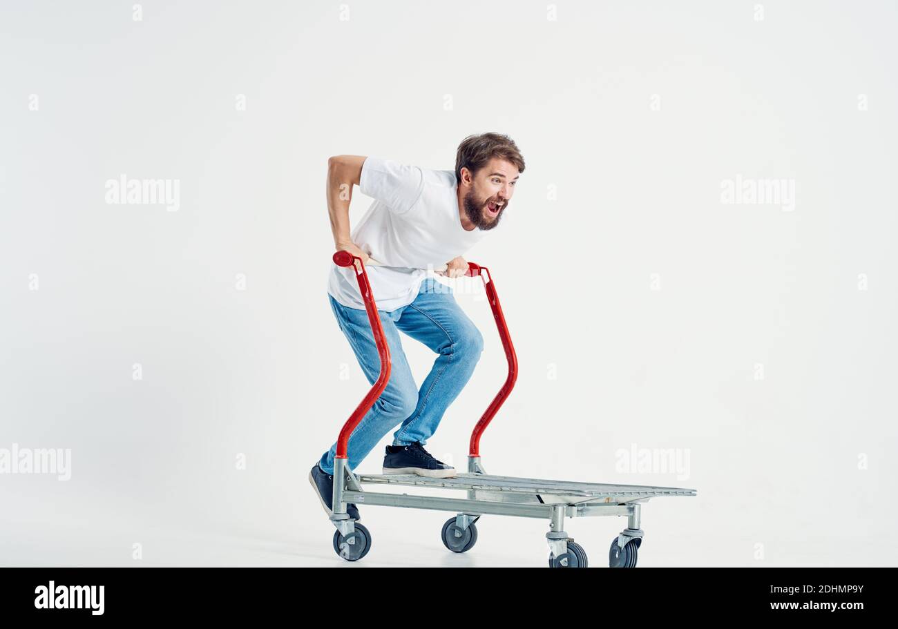 man with a trolley in his hand on a light background transporting heavy ...