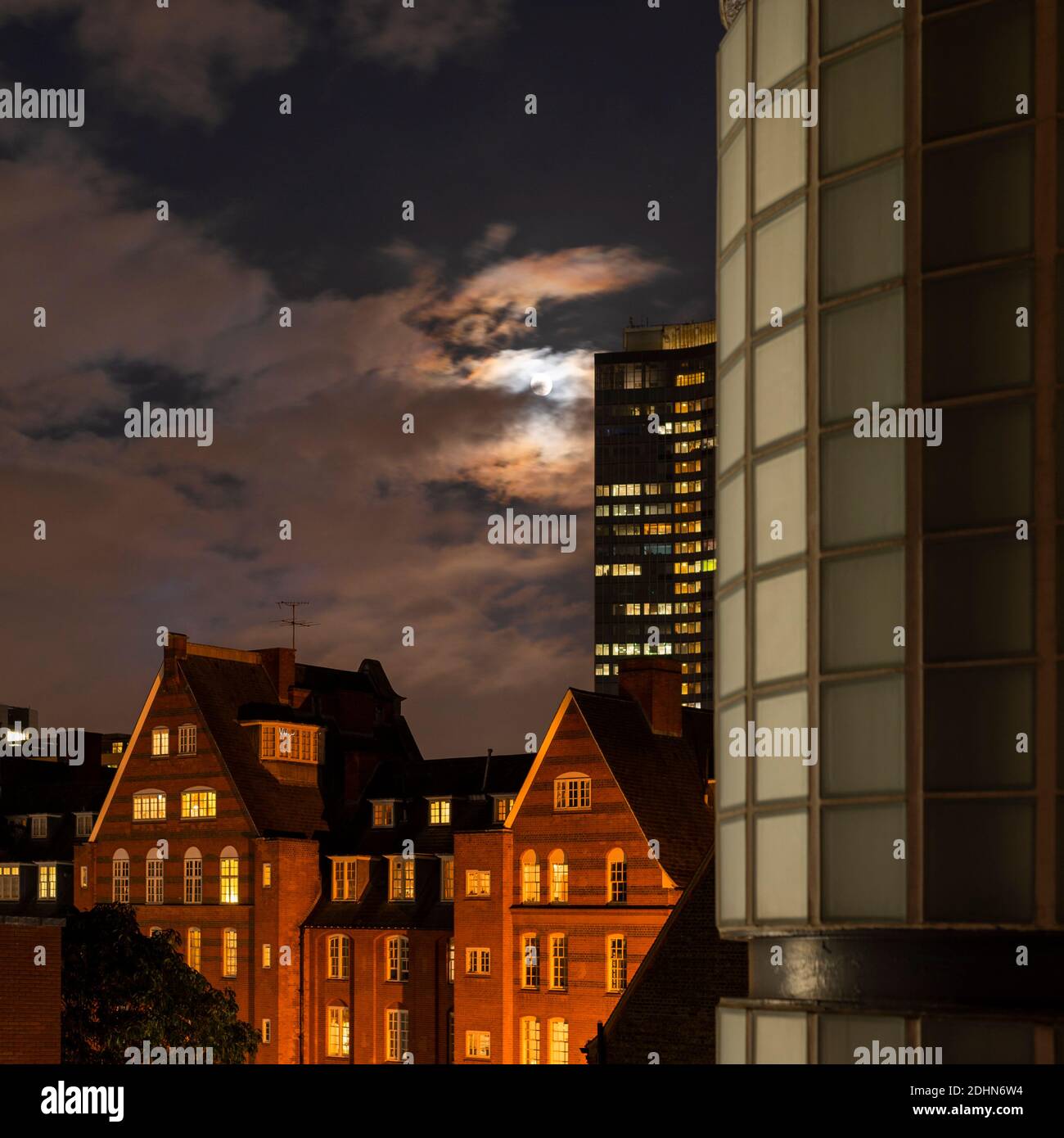Eery view of moonlit clouds over old redbrick building at night with ...