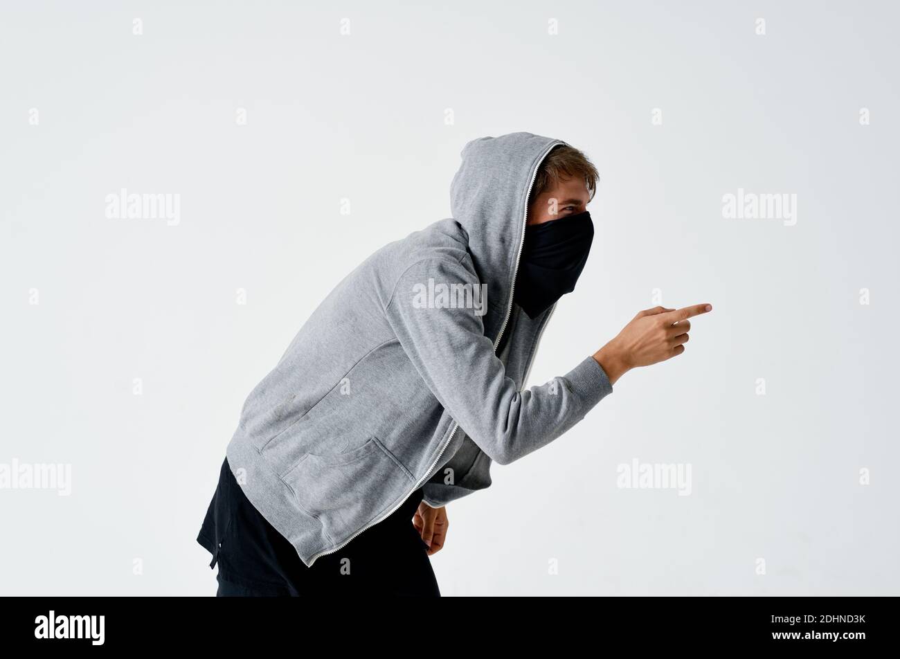 thief male hacker in a black mask and in a hood on a light background ...