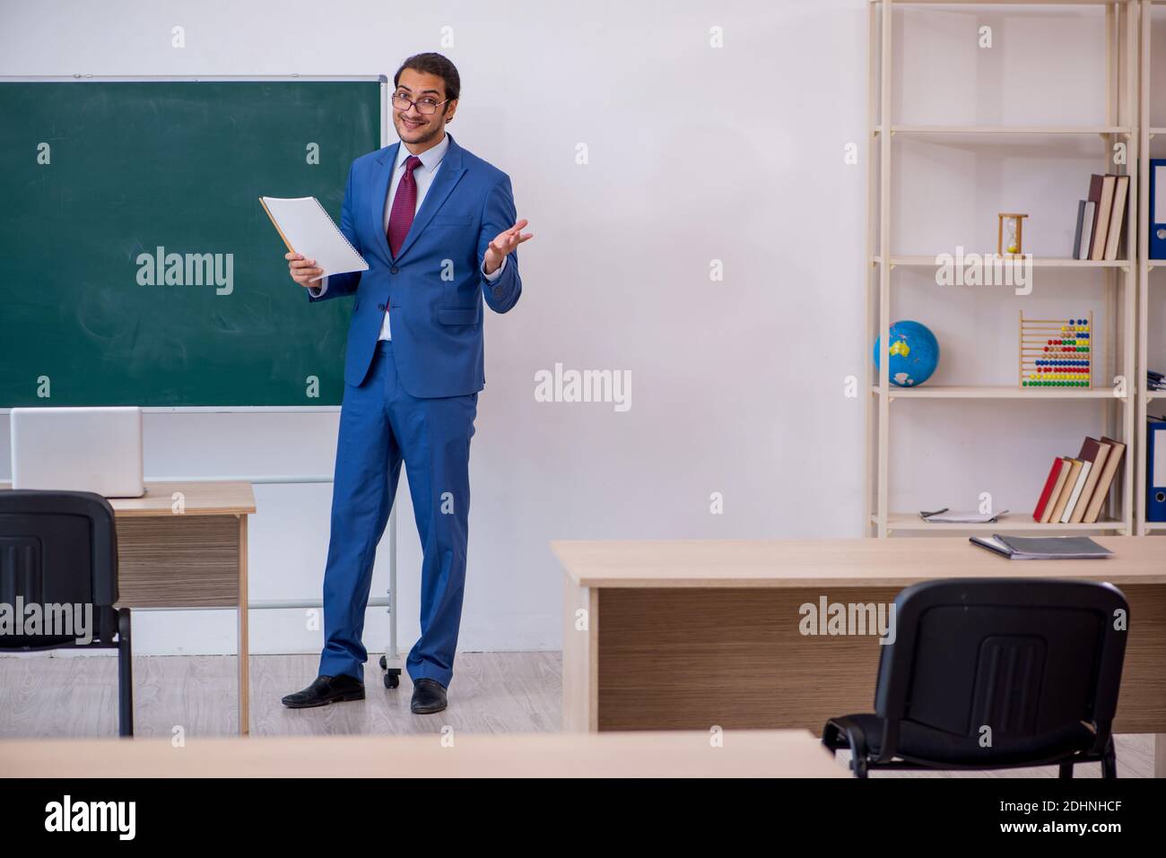 Young teacher in suit in front of green board Stock Photo - Alamy