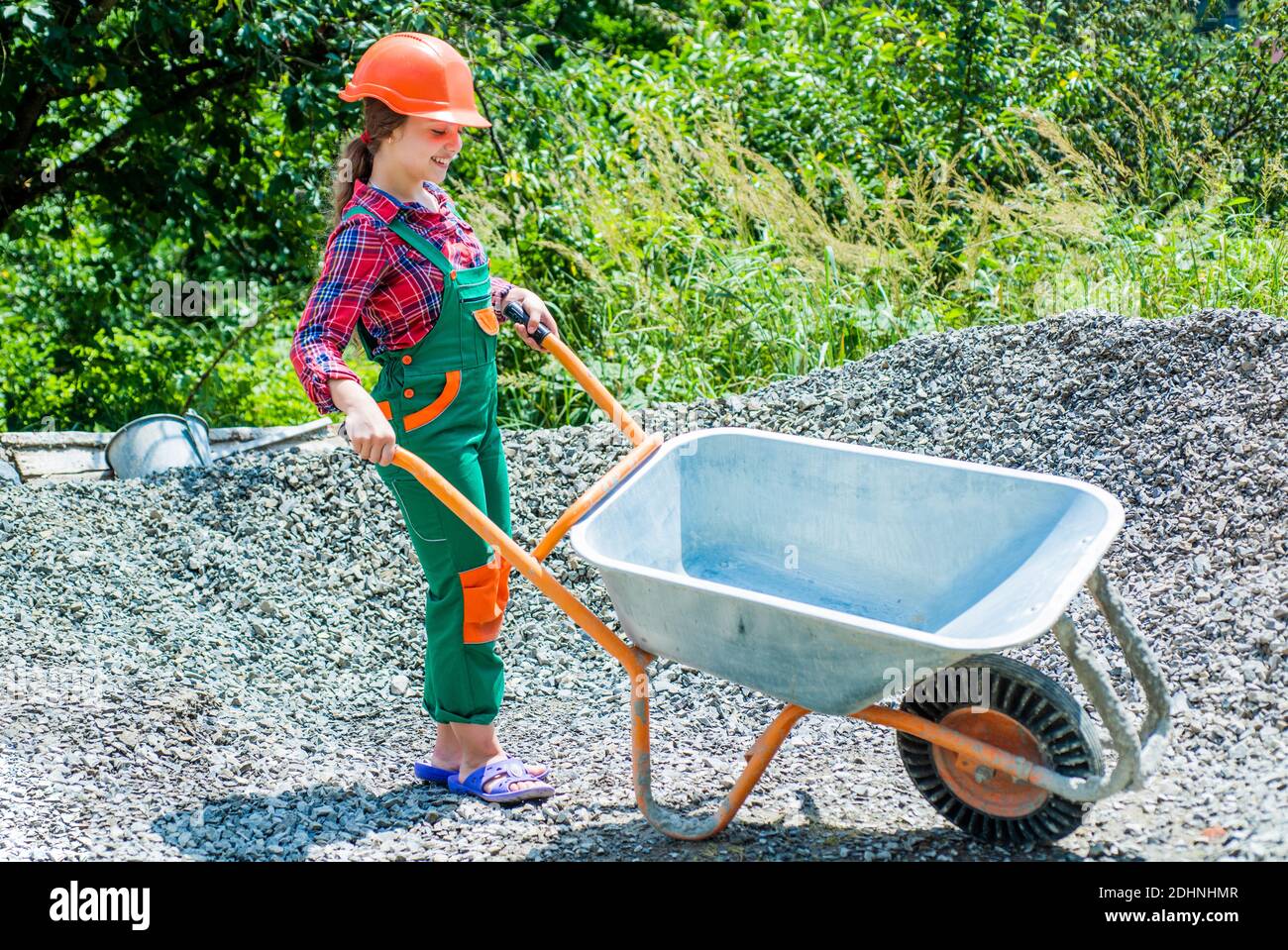 cheerful child laborer using building uniform and construction ...