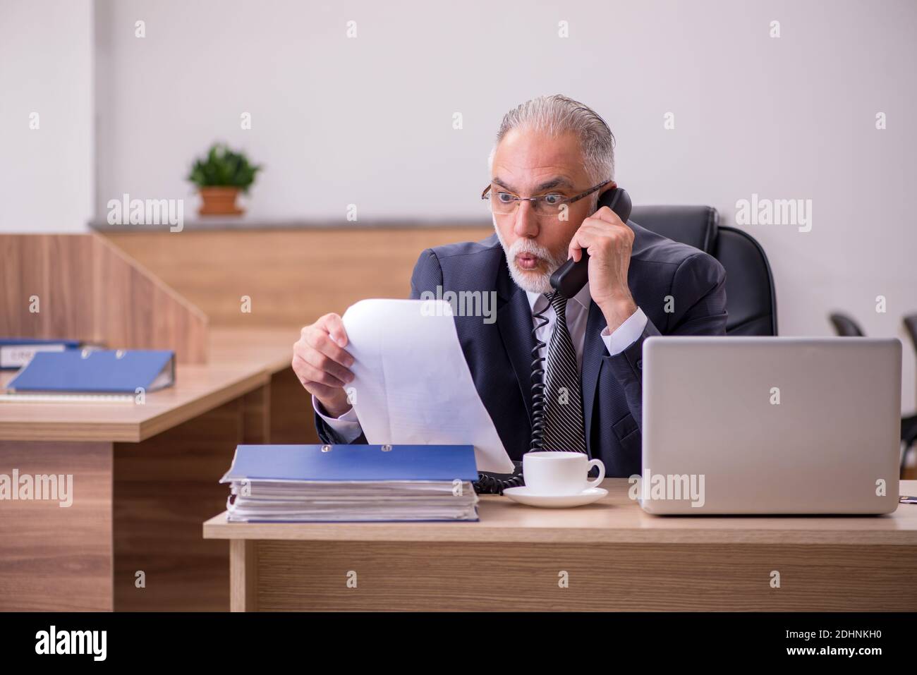 Old employee reading paper in the office Stock Photo - Alamy