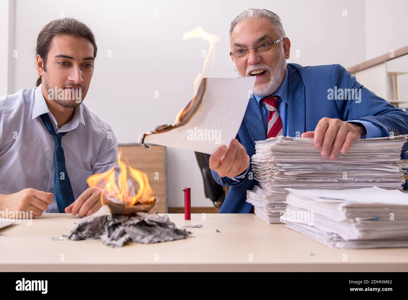 Male employee and his old boss burning papers at workplace Stock Photo ...