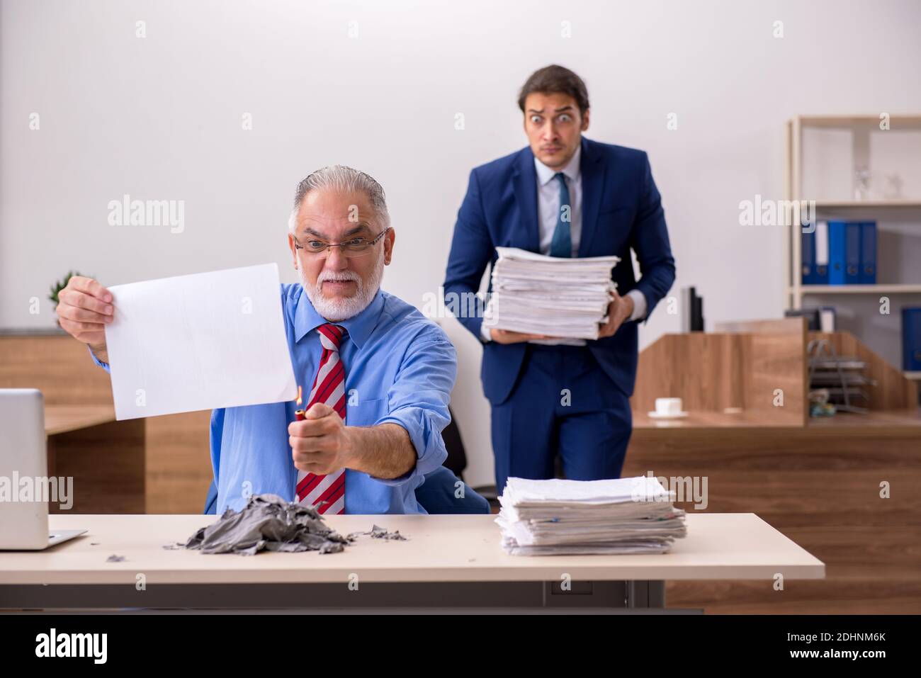 Male employee and his old boss burning papers at workplace Stock Photo ...