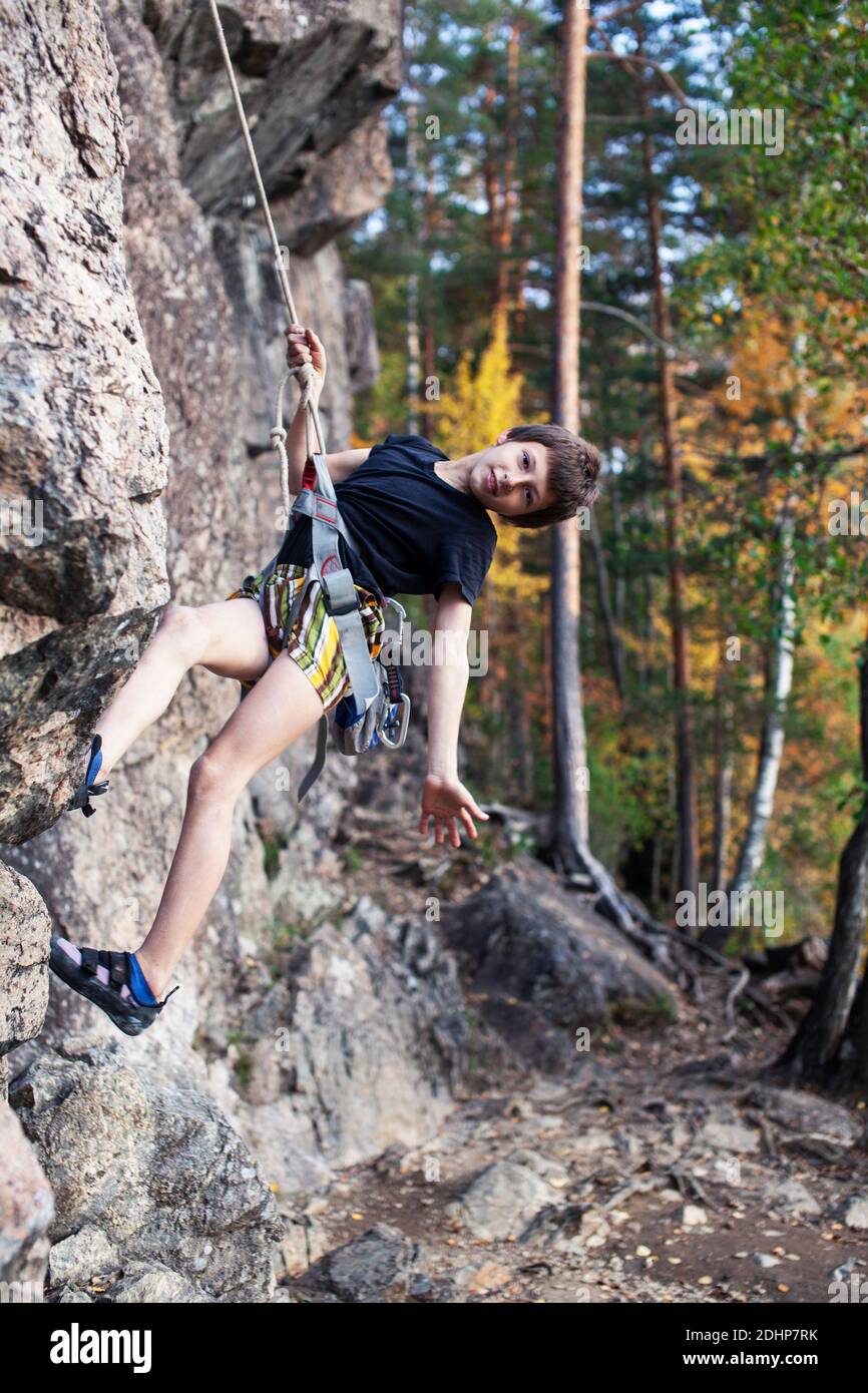 cute teen kid climbing on rock with insurance, lifestyle sport people ...