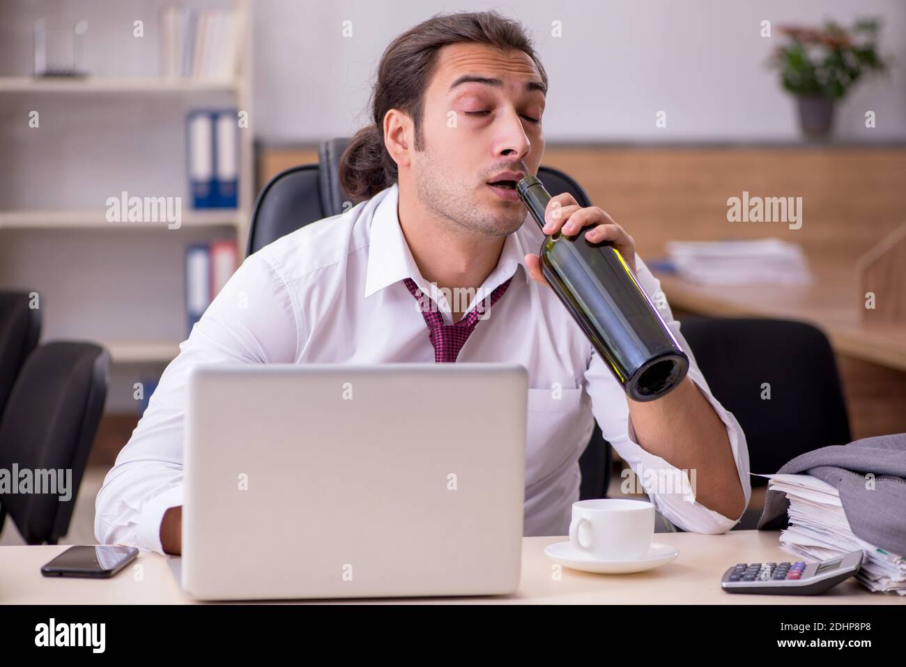 Young employee drinking alcohol in the office Stock Photo - Alamy
