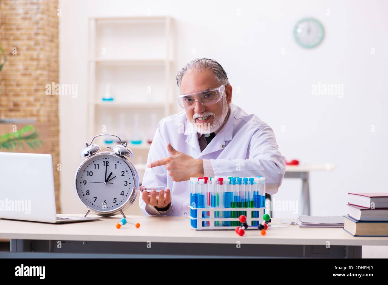 Senior male chemist in time management concept Stock Photo - Alamy