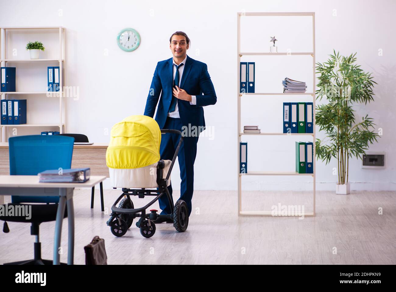 Young employee looking after kid at workplace Stock Photo - Alamy