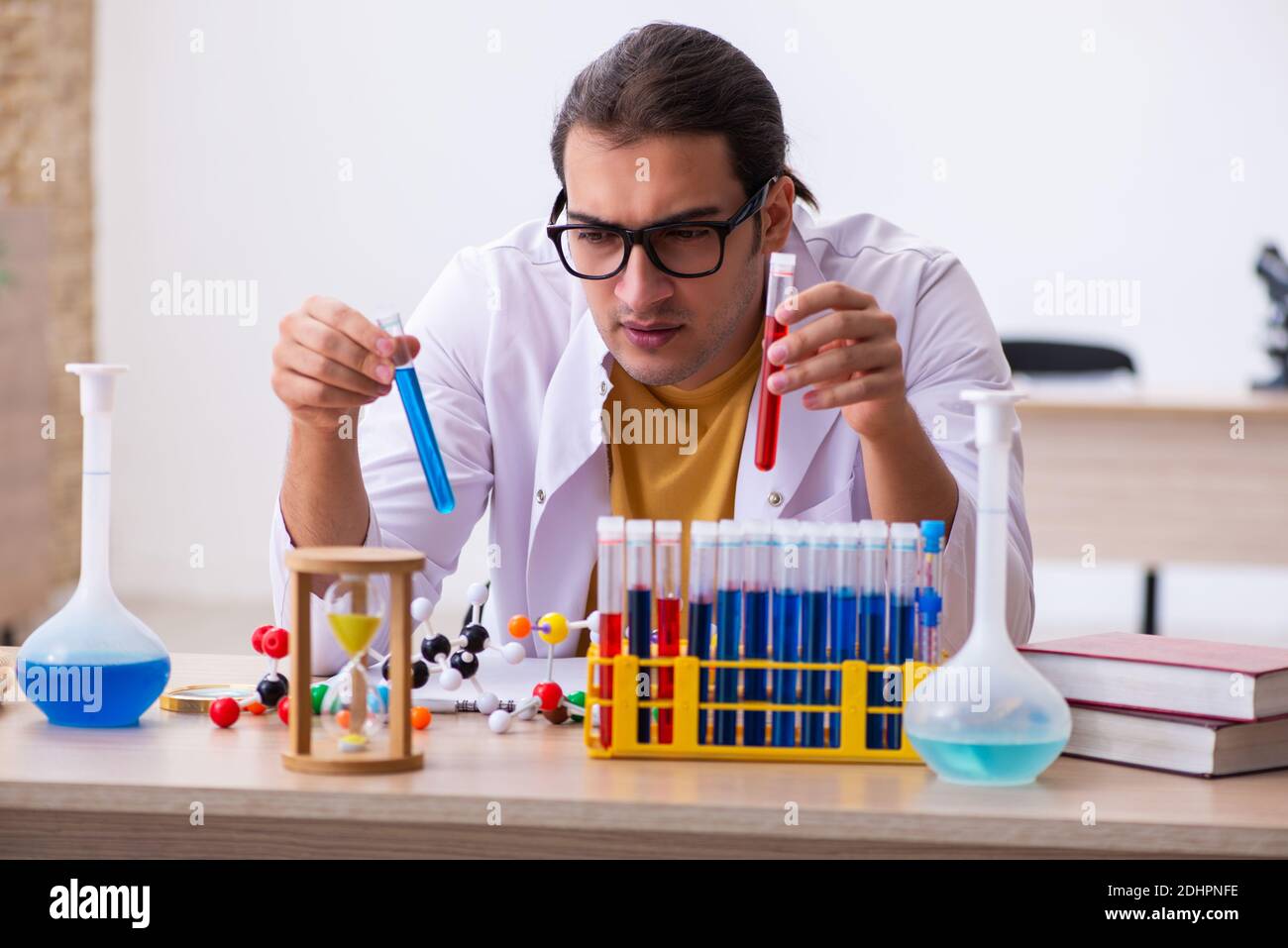 Young chemist in time management concept Stock Photo - Alamy