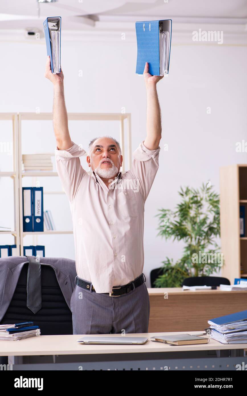 Senior male employee doing physical exercises at workplace Stock Photo ...