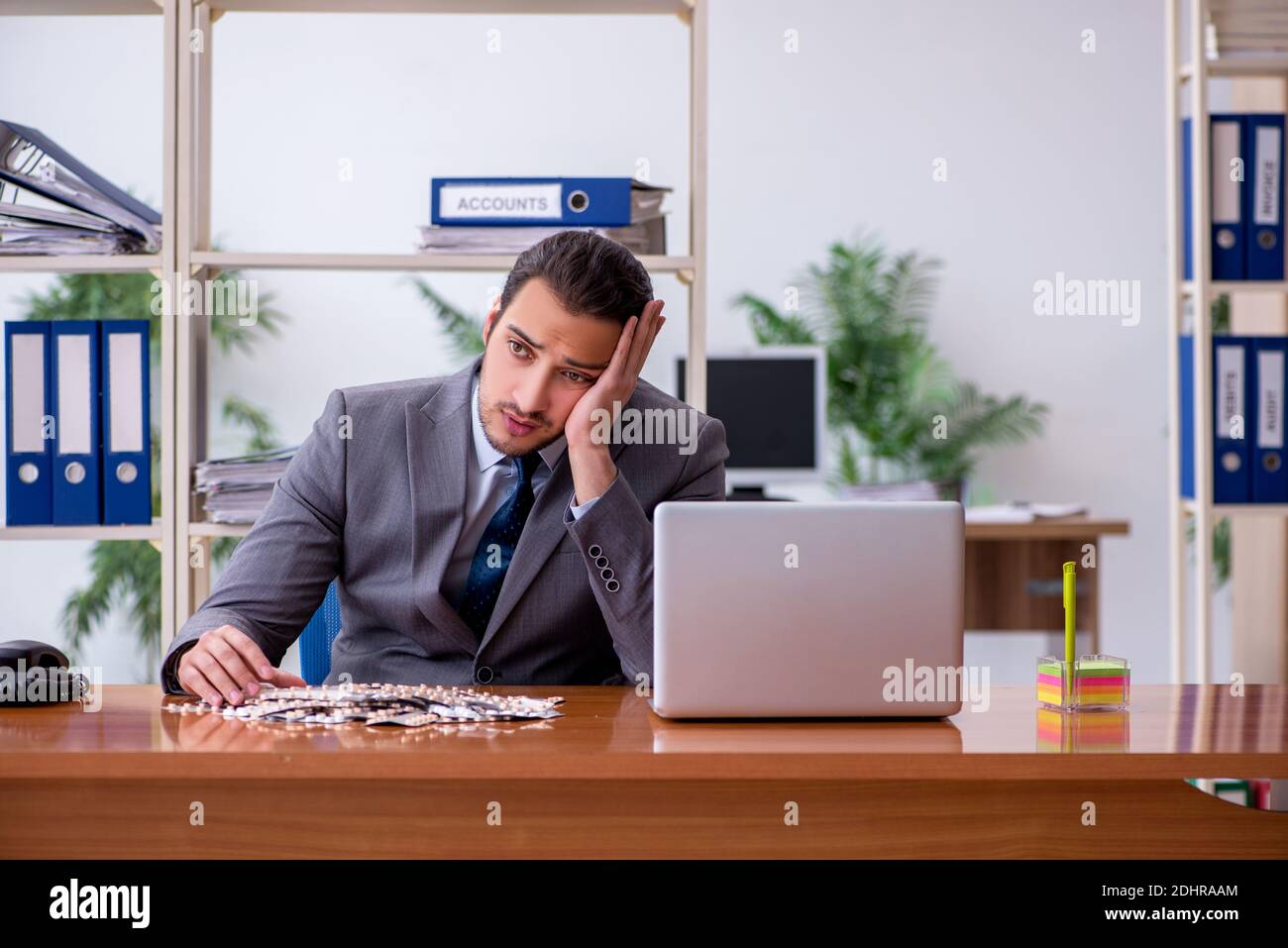 Male sick employee suffering at workplace Stock Photo - Alamy