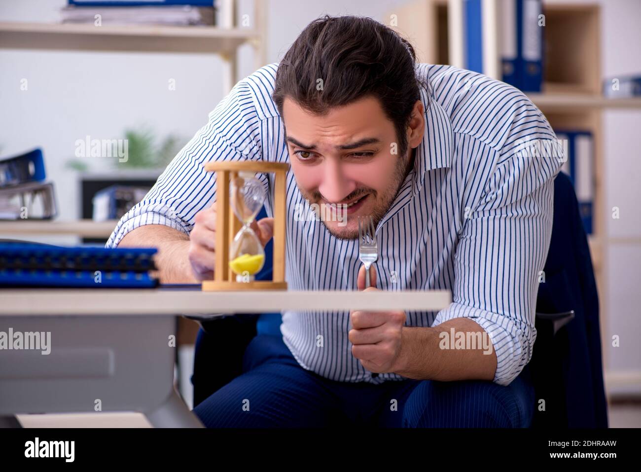 Hungry employee waiting for food in time management concept Stock Photo ...