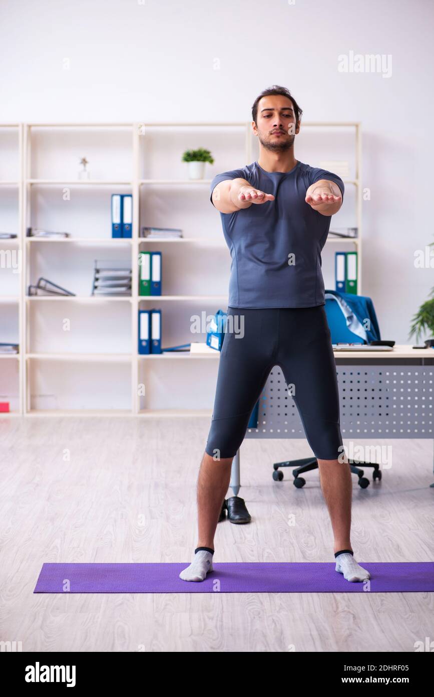 Young male employee doing sport exercises in the office Stock Photo - Alamy