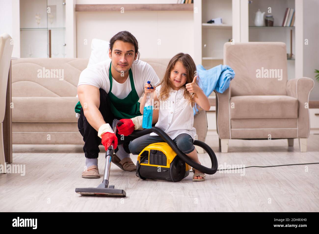 Young contractor cleaning the house with his small daughter Stock Photo ...