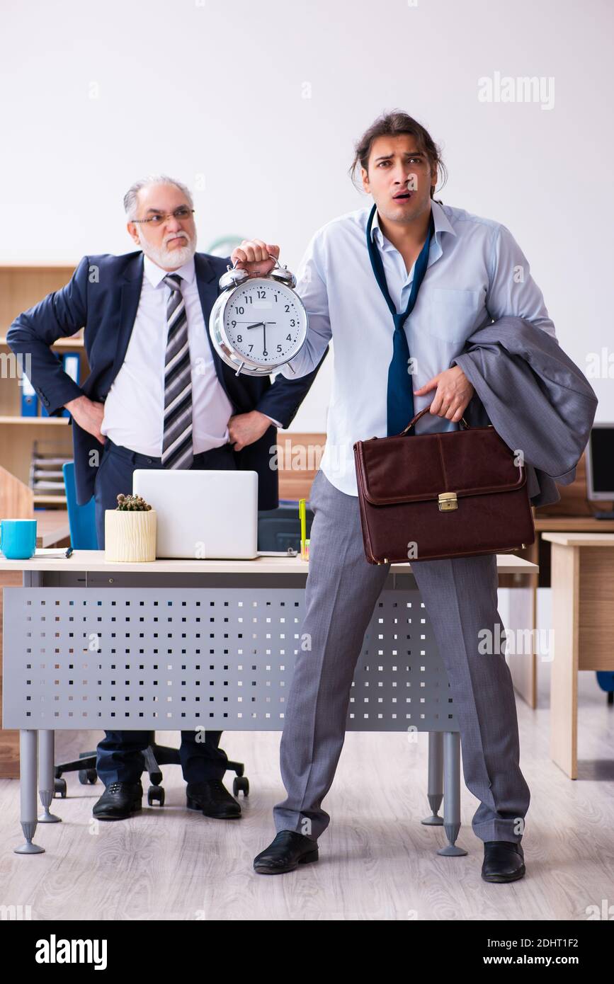 Old boss and young male employee in time management concept Stock Photo ...