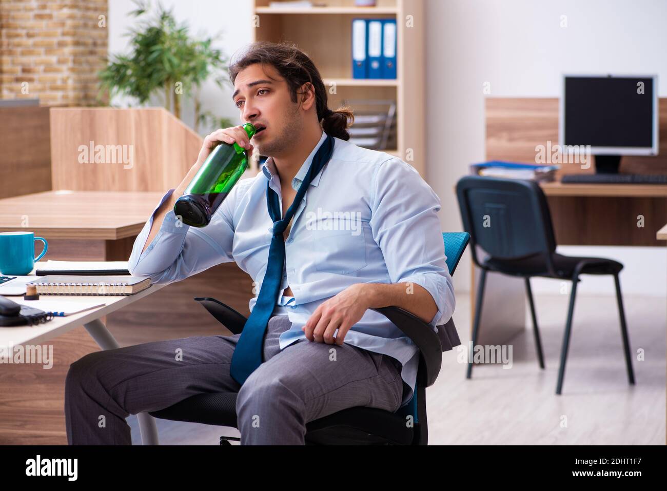 Male employee drinking alcohol at workplace Stock Photo - Alamy